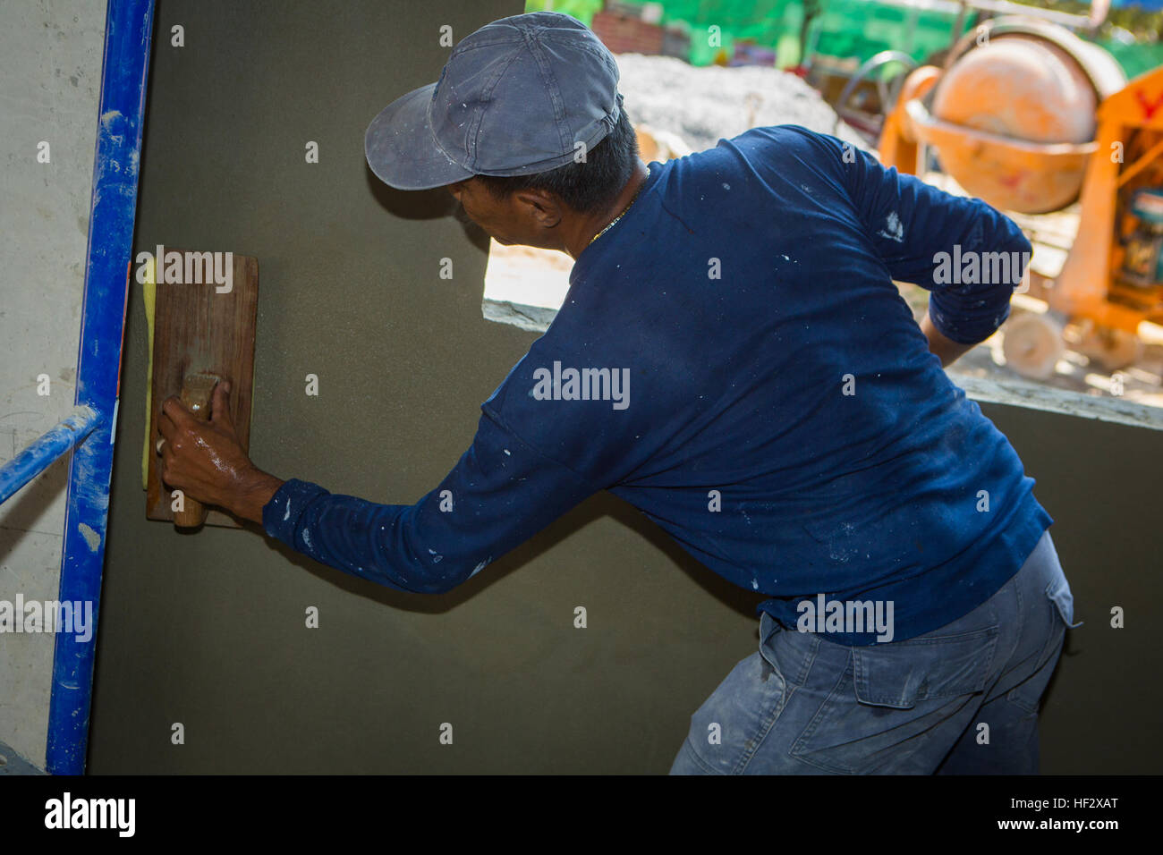 A soldier with the Royal Thai Air Force, applies plaster to a wall ...