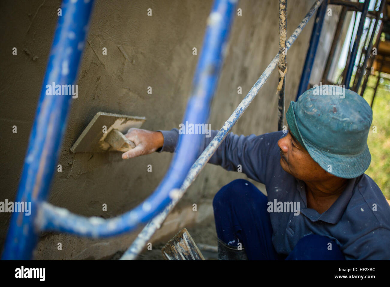 A soldier from the Royal Thai Air Force scrapes excess plaster from the ...