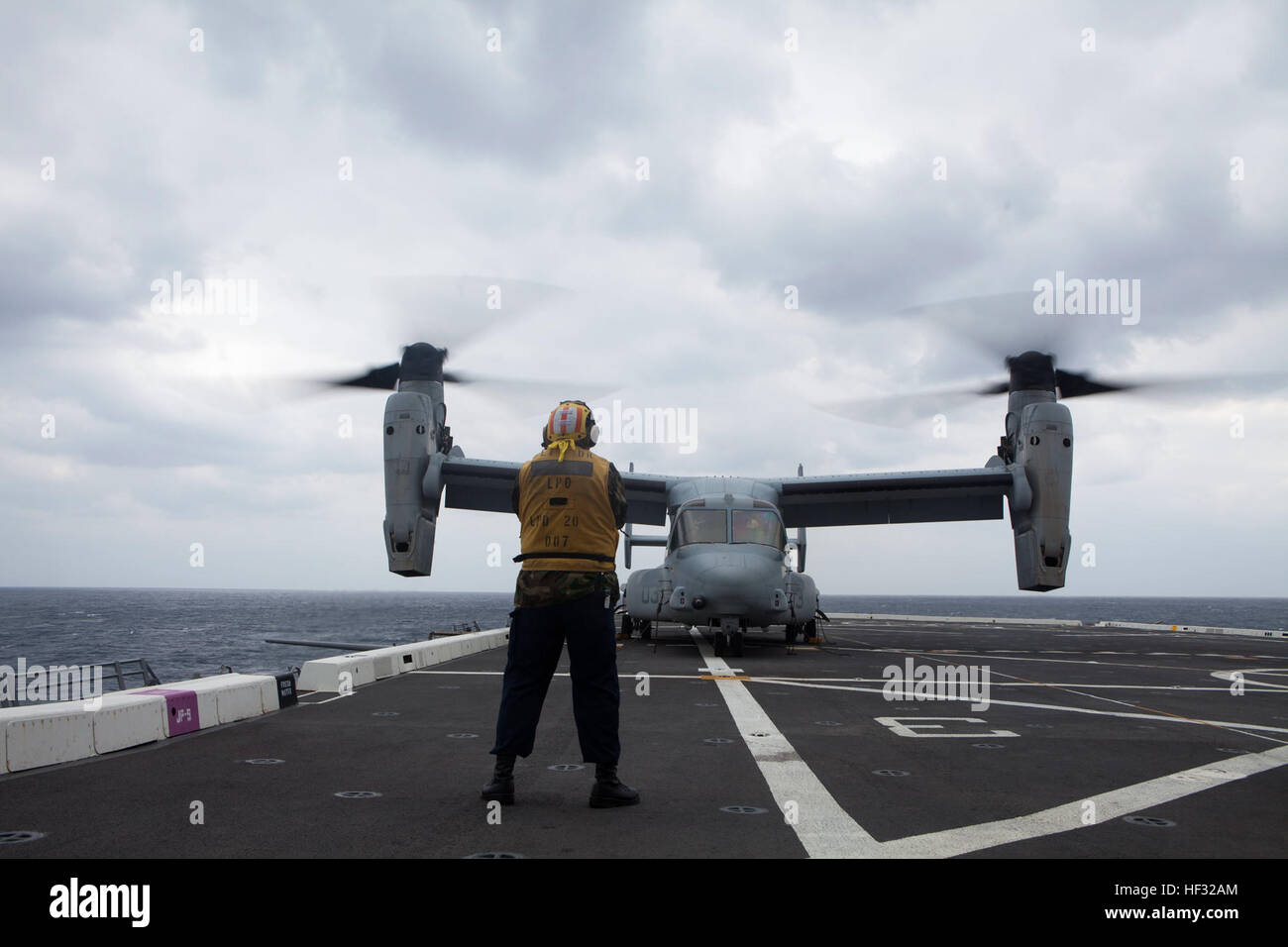 A U.S. Navy Sailor signals an MV-22 with Marine Medium Tiltrotor ...