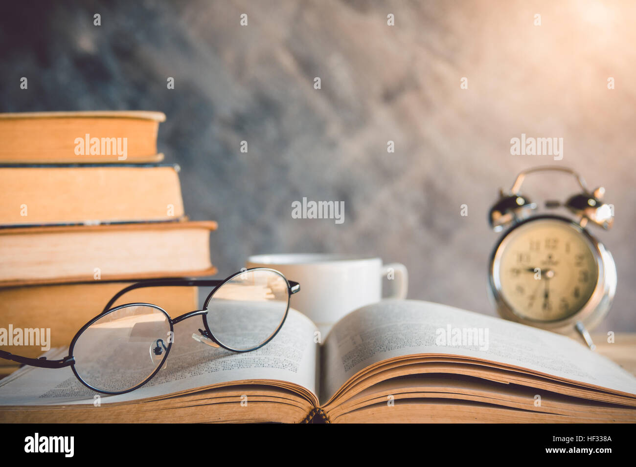 Reading glasses on old book with alarm clock Stock Photo - Alamy