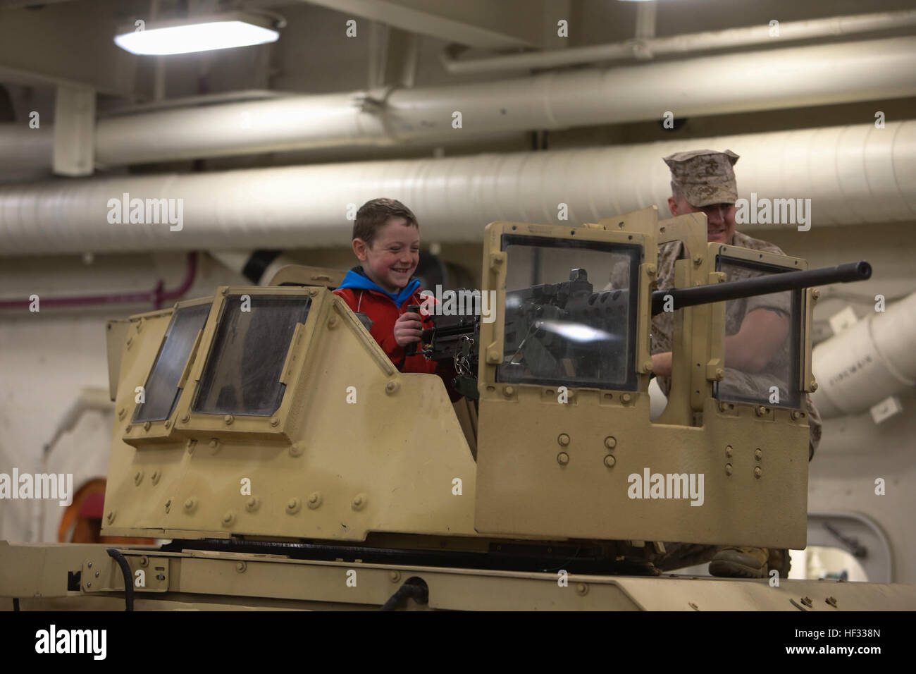 A child with a tour group aboard the USS Arlington mans the Humvee ...