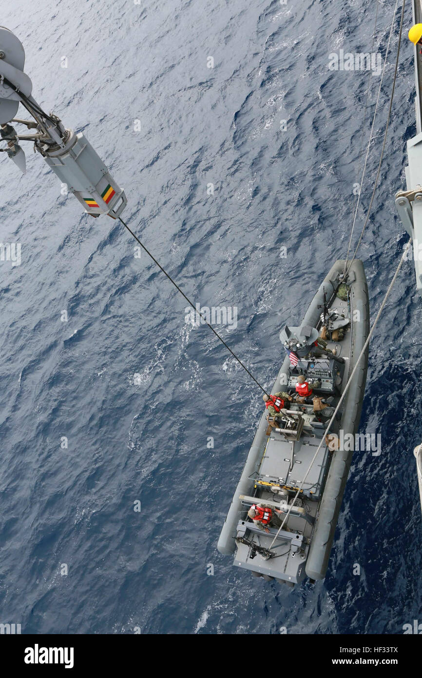 A rigid-hull inflatable boat is lowered from the USS Anchorage (LPD 23 ...