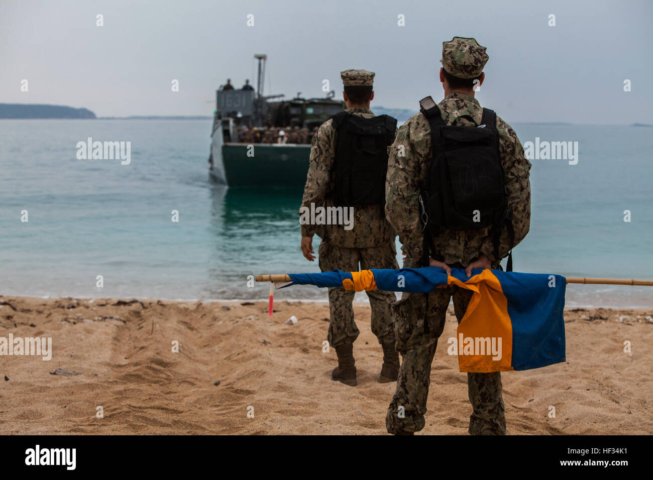 U.S. Navy Beach Masters with Naval Beach Unit 7, guide a landing craft ...