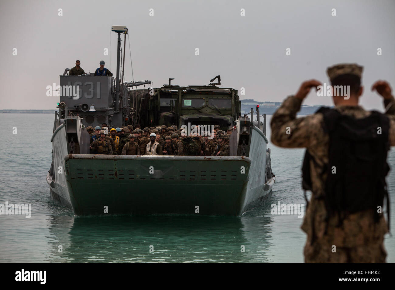 U.S. Navy Beach Masters with Naval Beach Unit 7, guide a landing craft ...