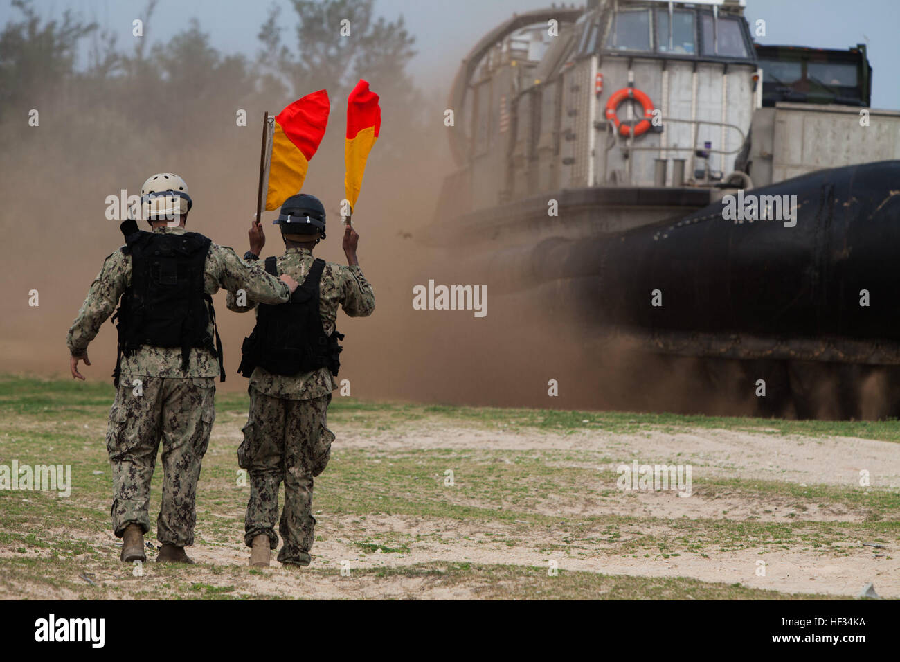 U.S. Navy Beach Masters with Naval Beach Unit 7, guide a landing craft ...