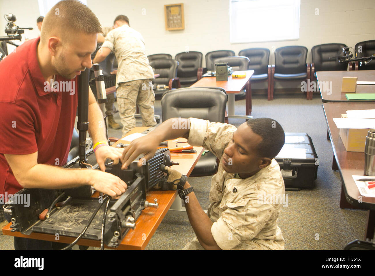Mr. Daniel Swick, a civilian contractor, helps Sgt. Kharlange Joseph ...