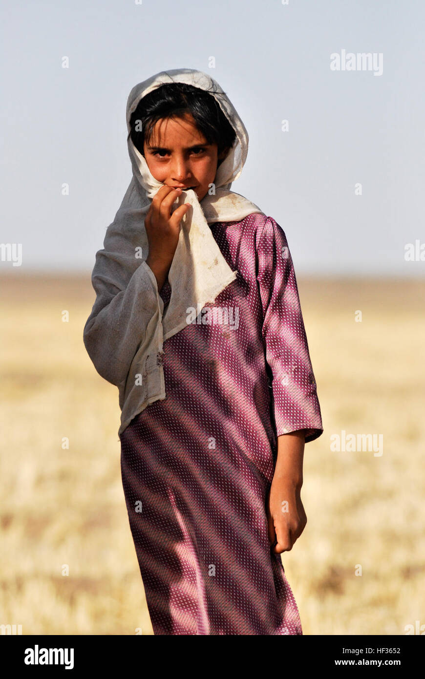 An Afghan girl stops to stare at the camera before running back to her ...