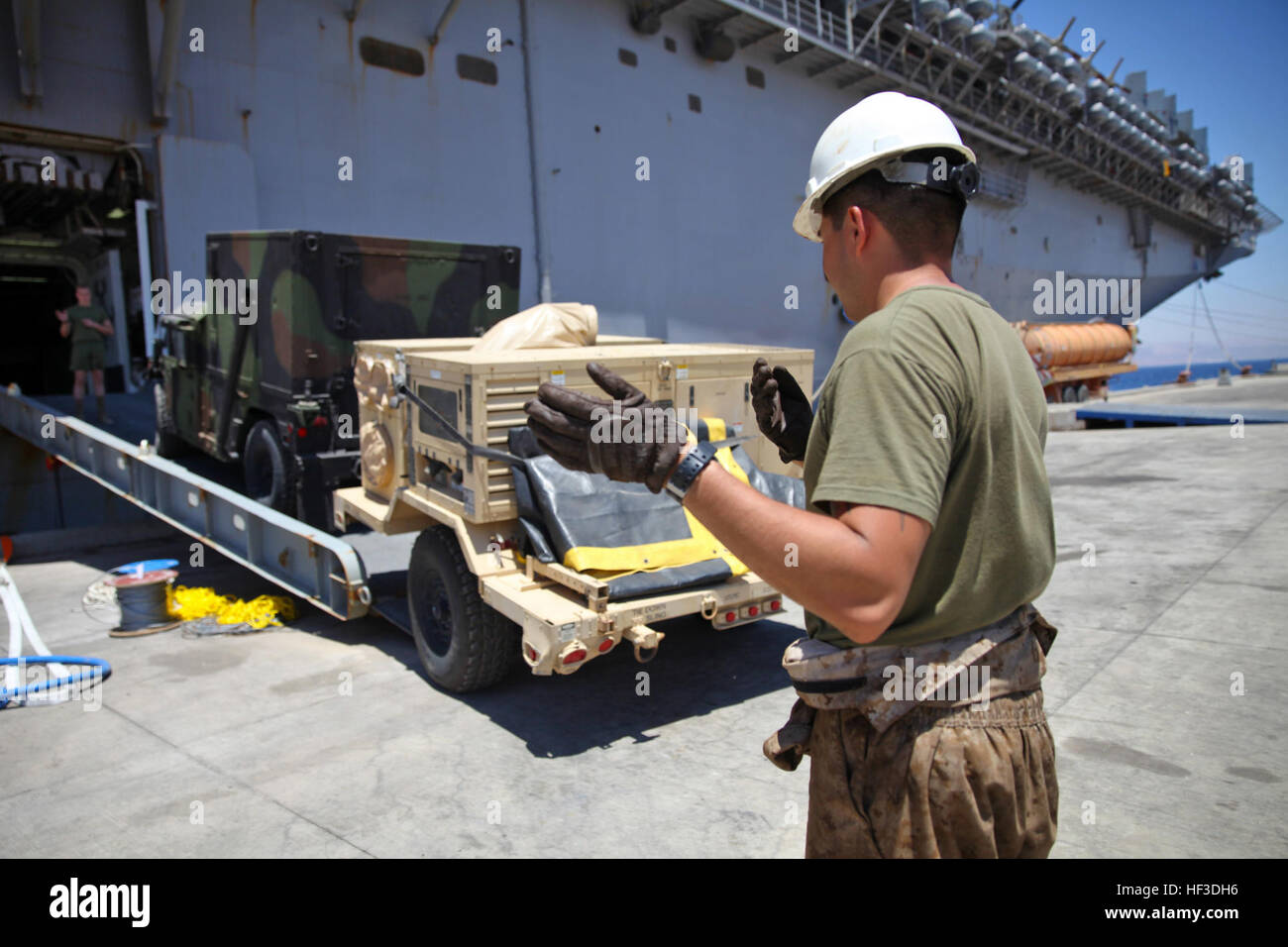 A Marine with the 24th Marine Expeditionary Unit (MEU) directs a Humvee ...