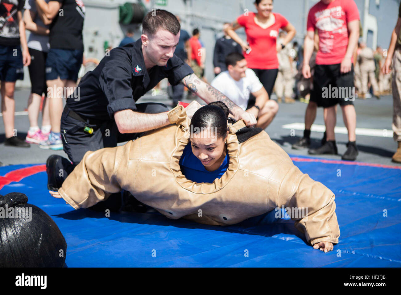A Navy sailor helps another sailor into a sumo suit during the Fourth ...
