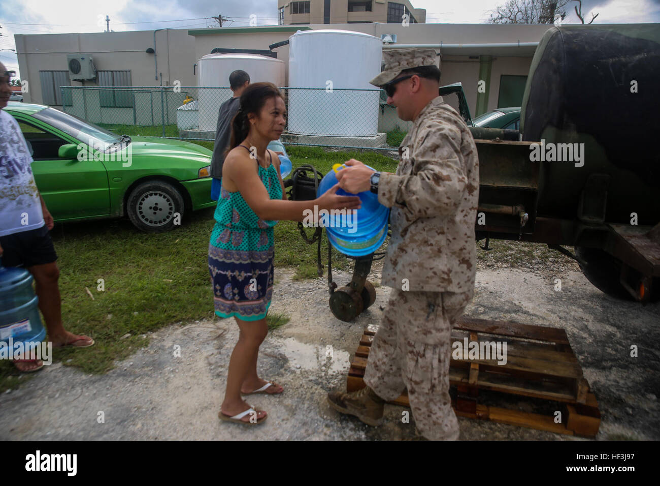 U.S. Navy Seaman Joshua Peffley hands water to a local woman as a part ...
