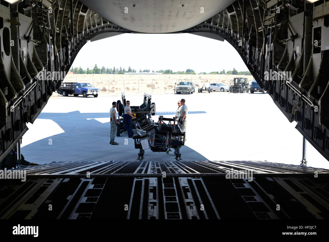 Airmen assigned to the 144th Fighter Wing load cargo aboard a C-17 ...