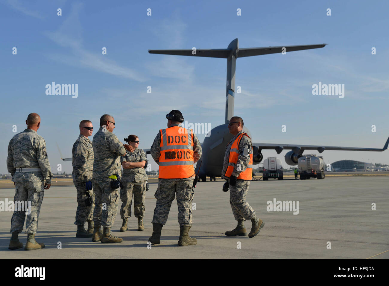 Airmen assigned to the 144th Fighter Wing wait to load cargo aboard a C ...