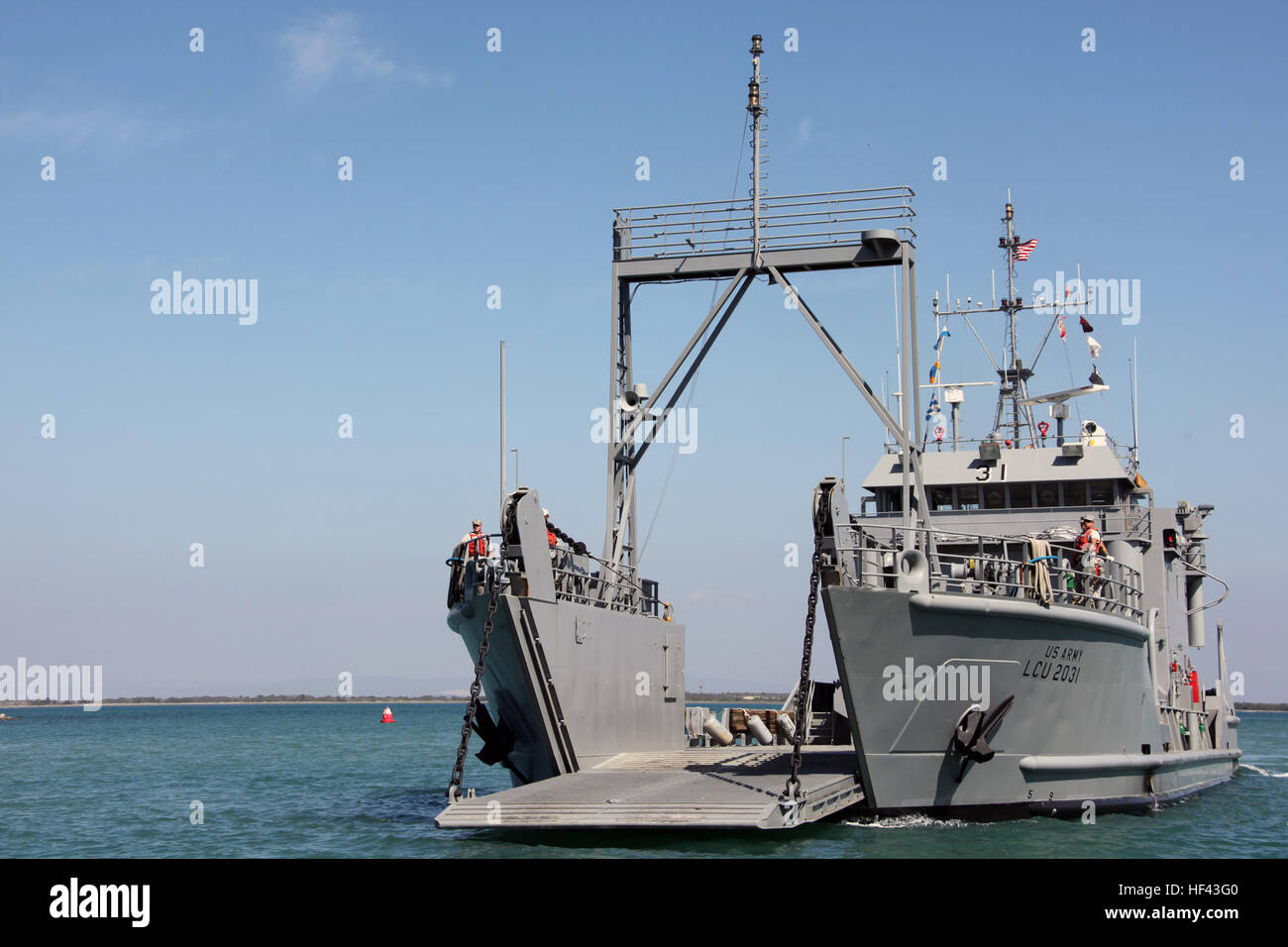A U.S. Army landing craft pulls up to a beach to unload equipment from ...