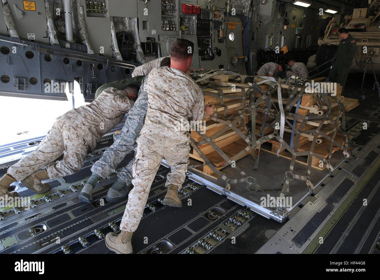 U.S. Marines and Airmen work hand-in-hand to load a pallet, filled with ...
