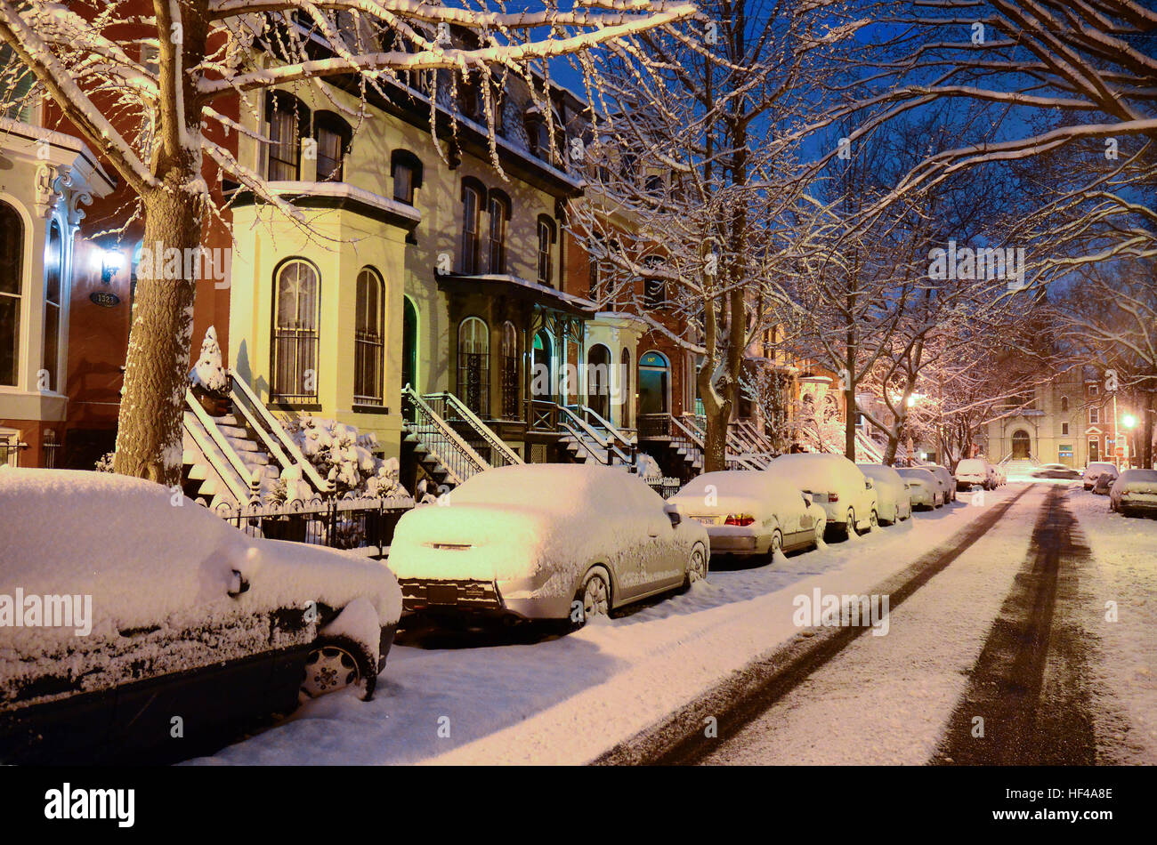 Old Victorian row houses and snow covered cars on a residential street ...