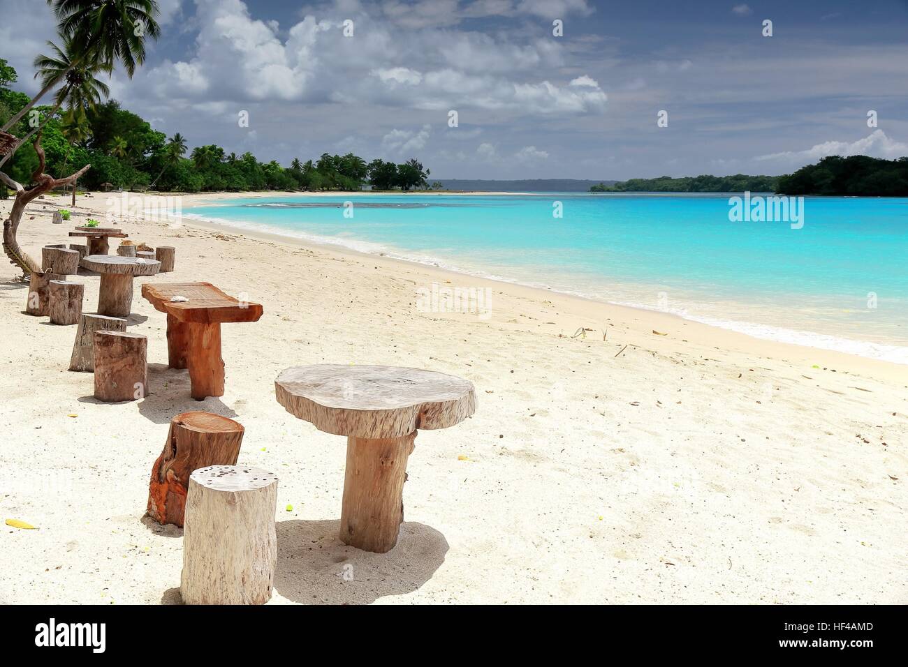 Set of wooden stools and tables for visitors placed under coconut palm ...