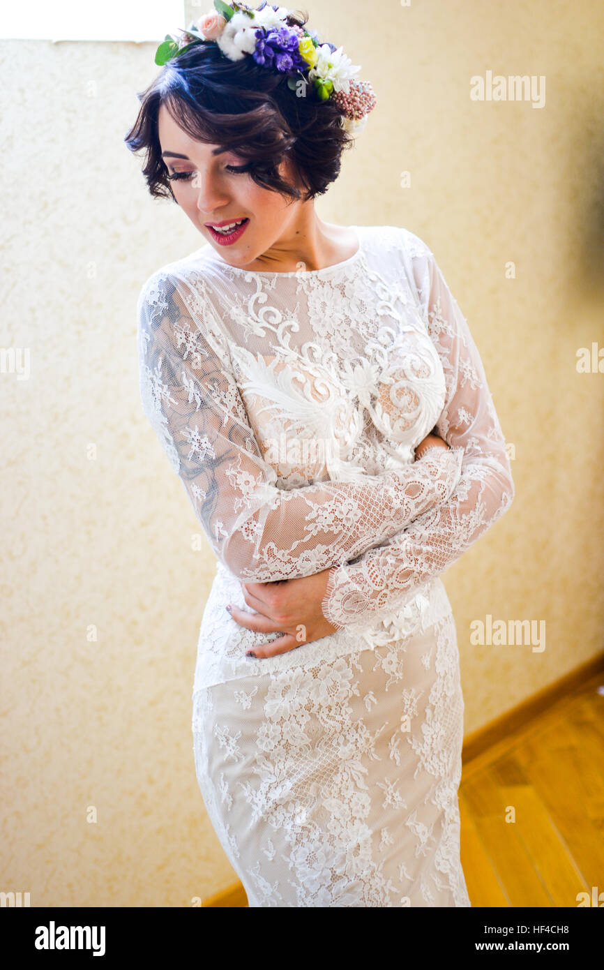 Beautiful bride in white lace dress and flowers in hair. Waiting in ...