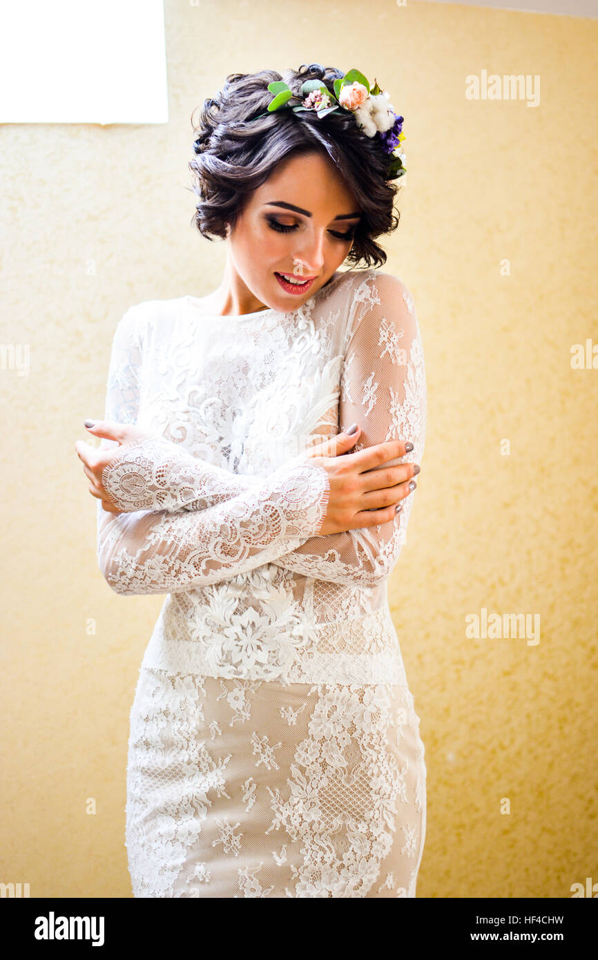 Beautiful bride in white lace dress and flowers in hair. Waiting in ...