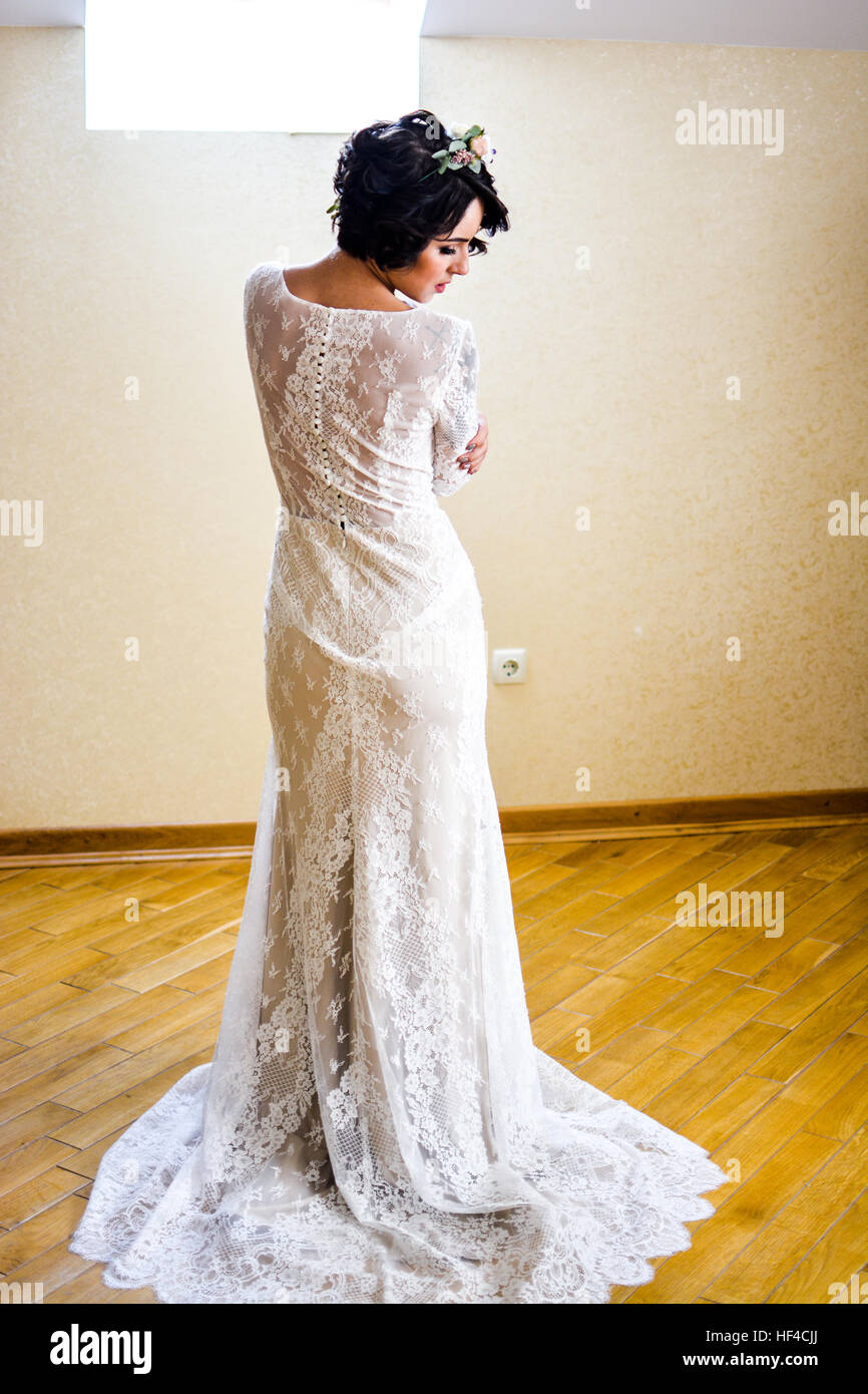 Beautiful bride in white lace dress and flowers in hair. Waiting in ...