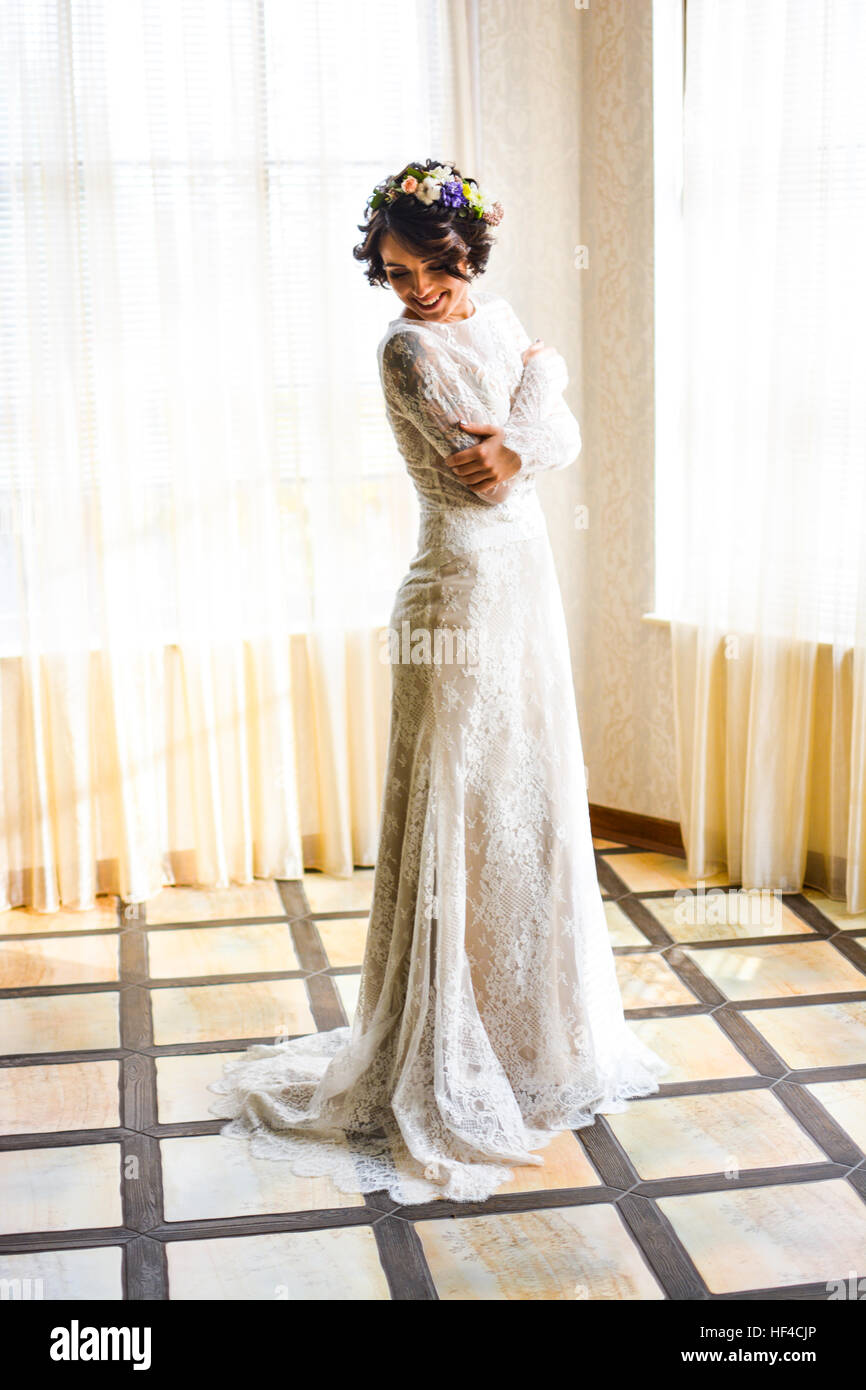 Beautiful bride in white lace dress and flowers in hair. Waiting in ...
