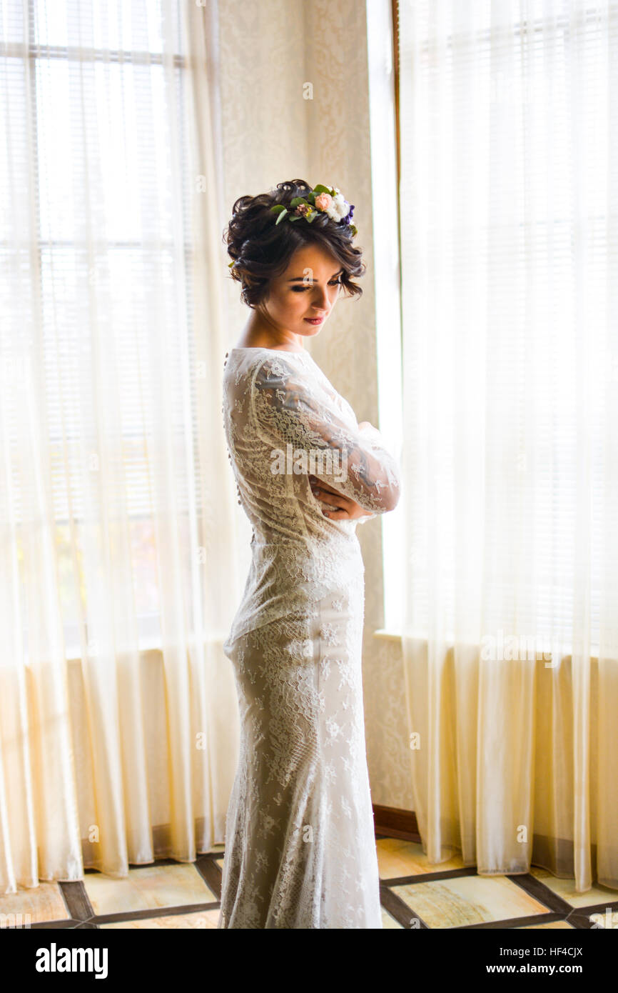 Beautiful bride in white lace dress and flowers in hair. Waiting in ...