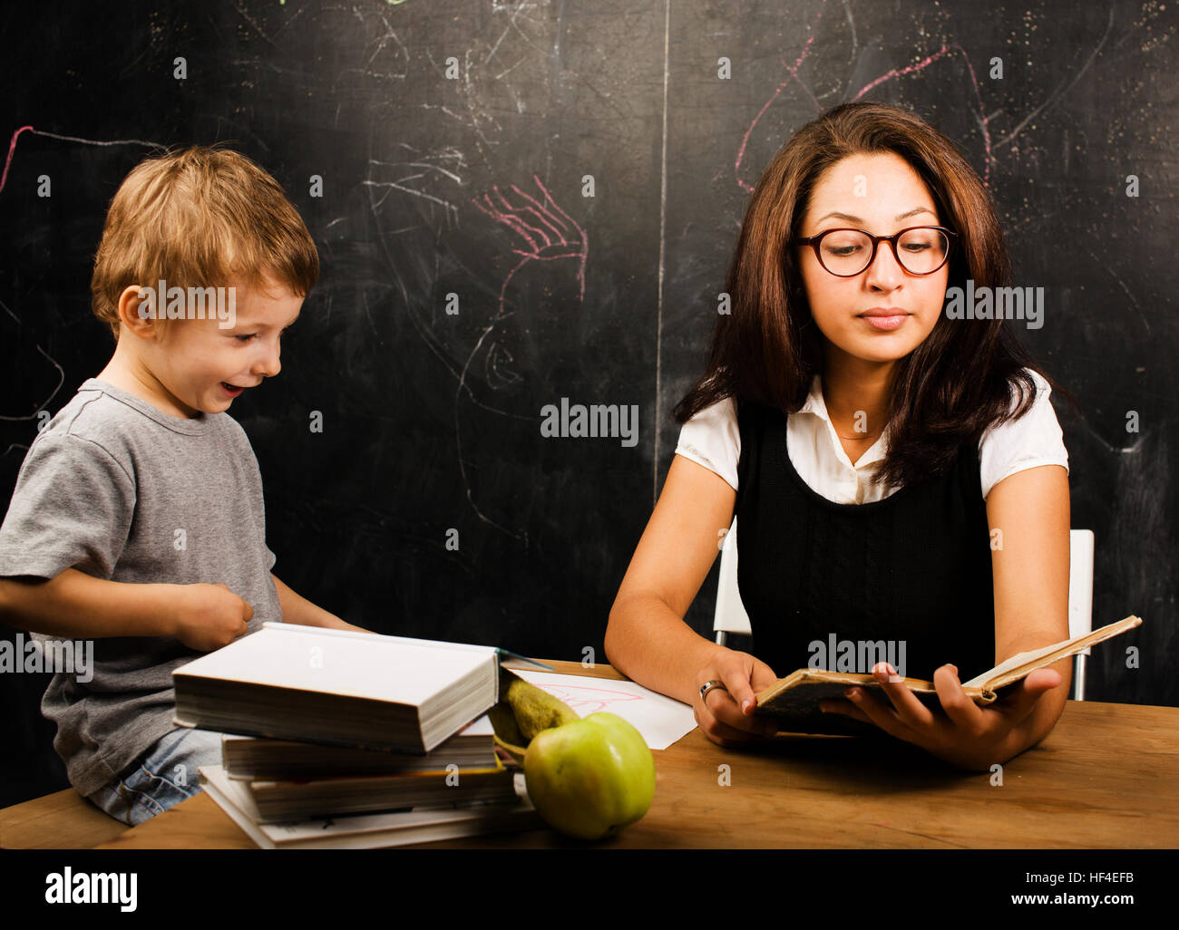 little cute boy with young teacher in classroom studying at blac Stock ...