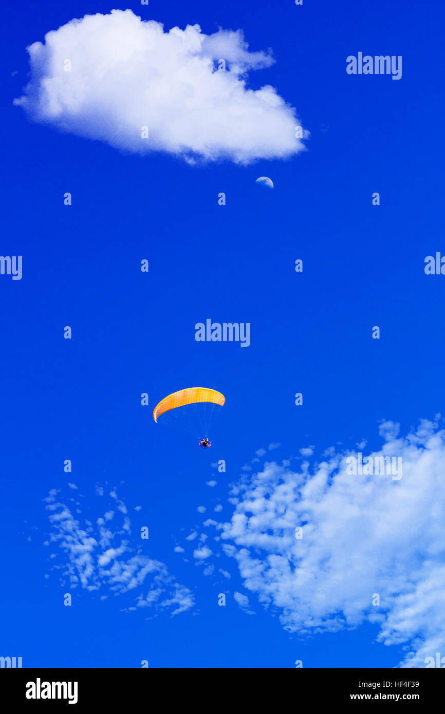 paraglider flying in a blue sunny sky with clouds Stock Photo - Alamy