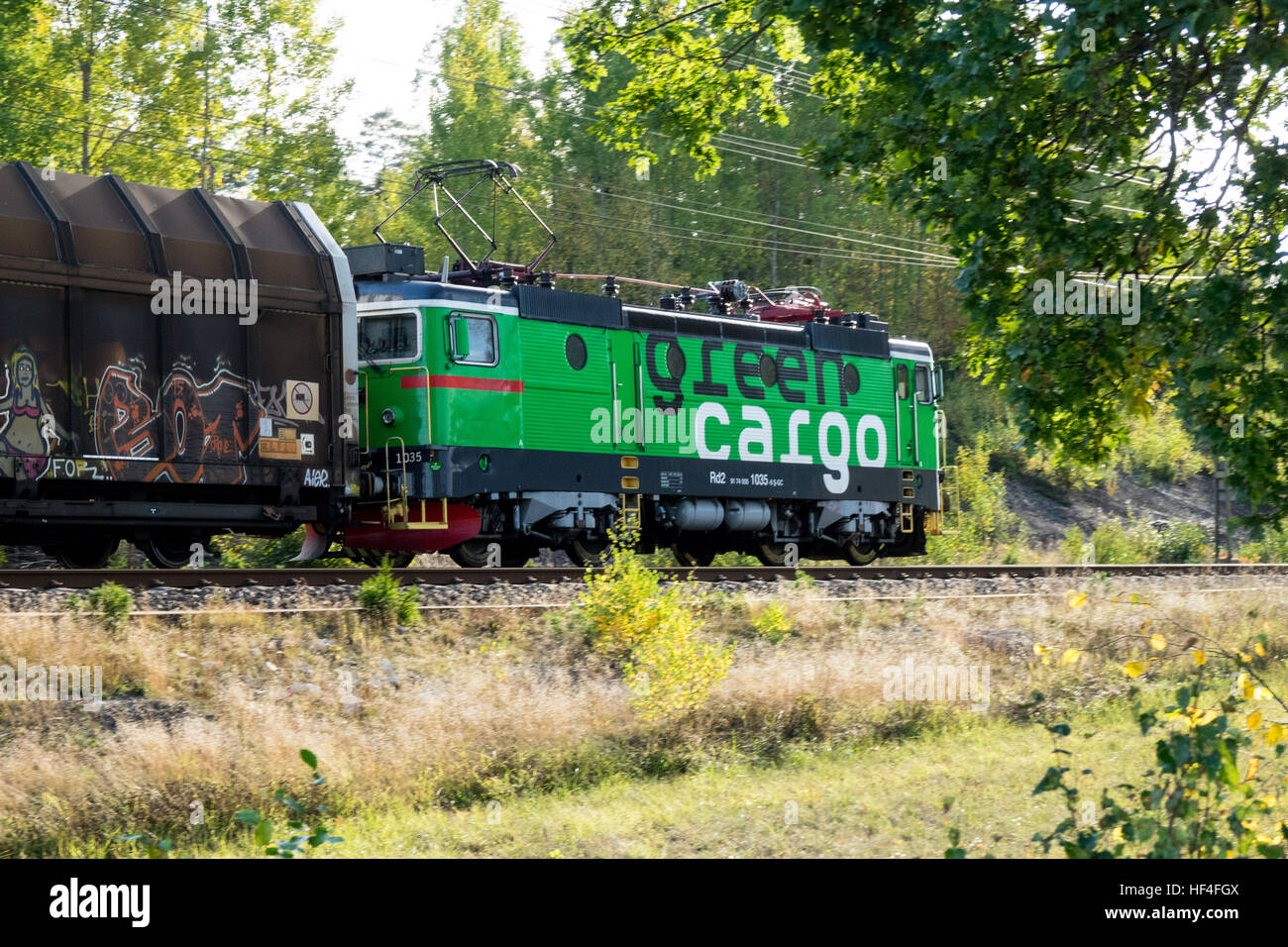 Green cargo train in the fall colored landscape Stock Photo - Alamy