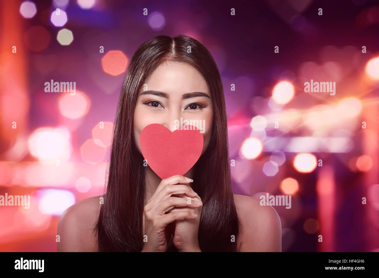 Beautiful asian woman holding a red heart shape in front of her face ...