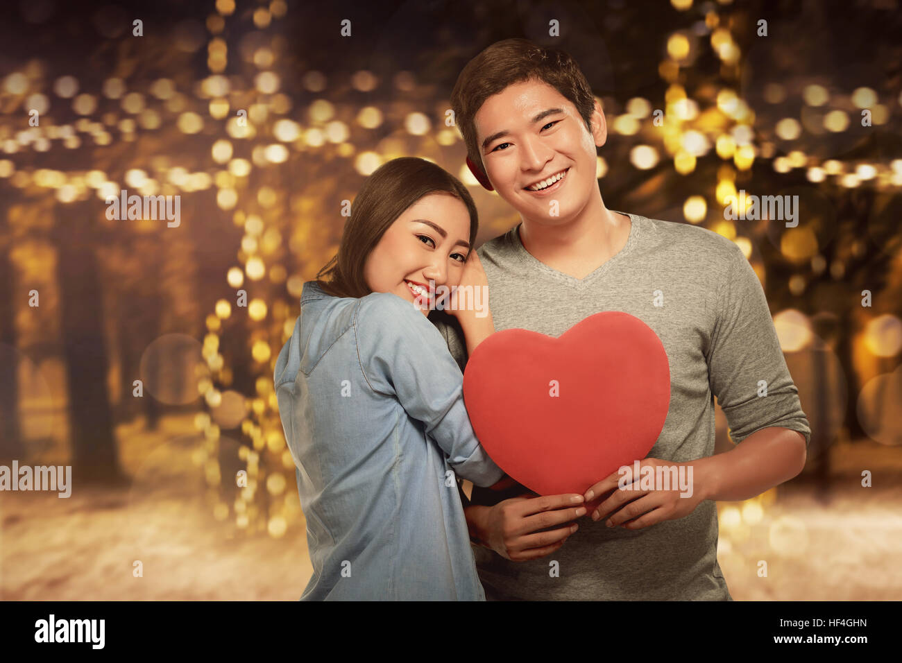 Young asian couple standing in embrace and holding heart shape on the ...