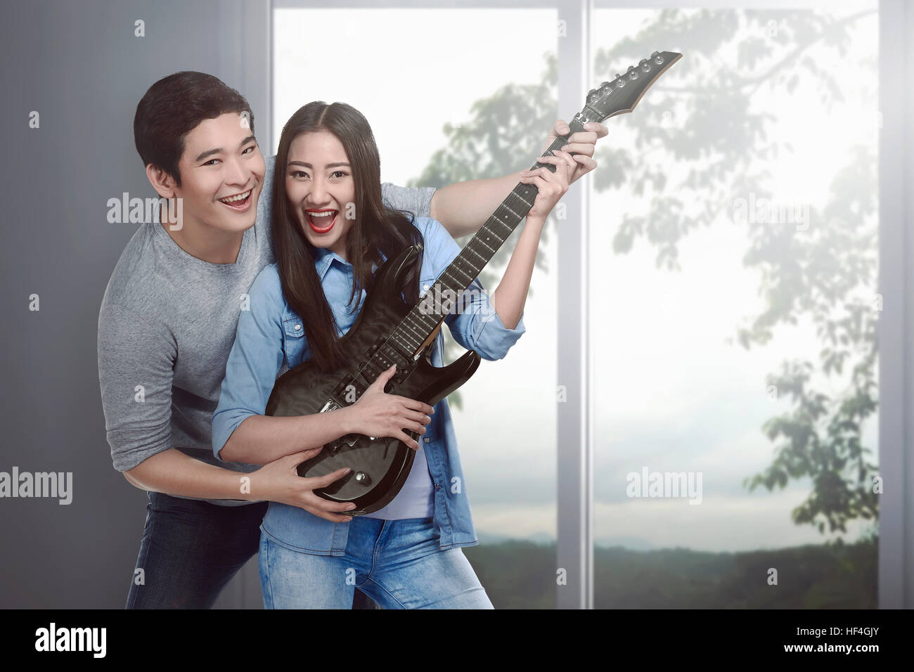 Attractive asian couple in love playing guitar in the home Stock Photo ...