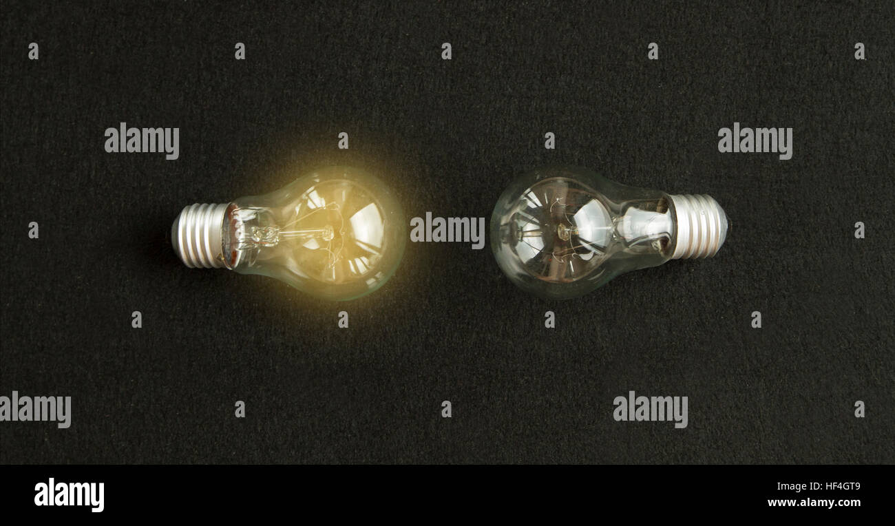 Idea concept with two bulbs, one bulb is with light on the black ...
