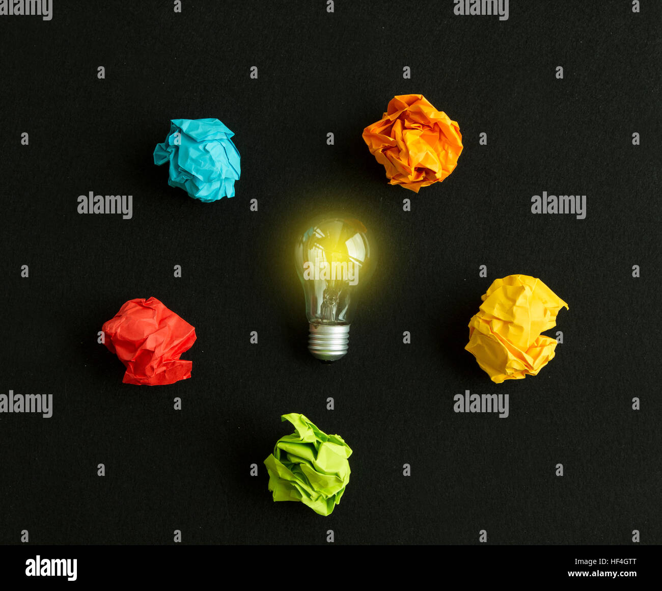 Idea concept with bulb and different colors paper wads on black ...