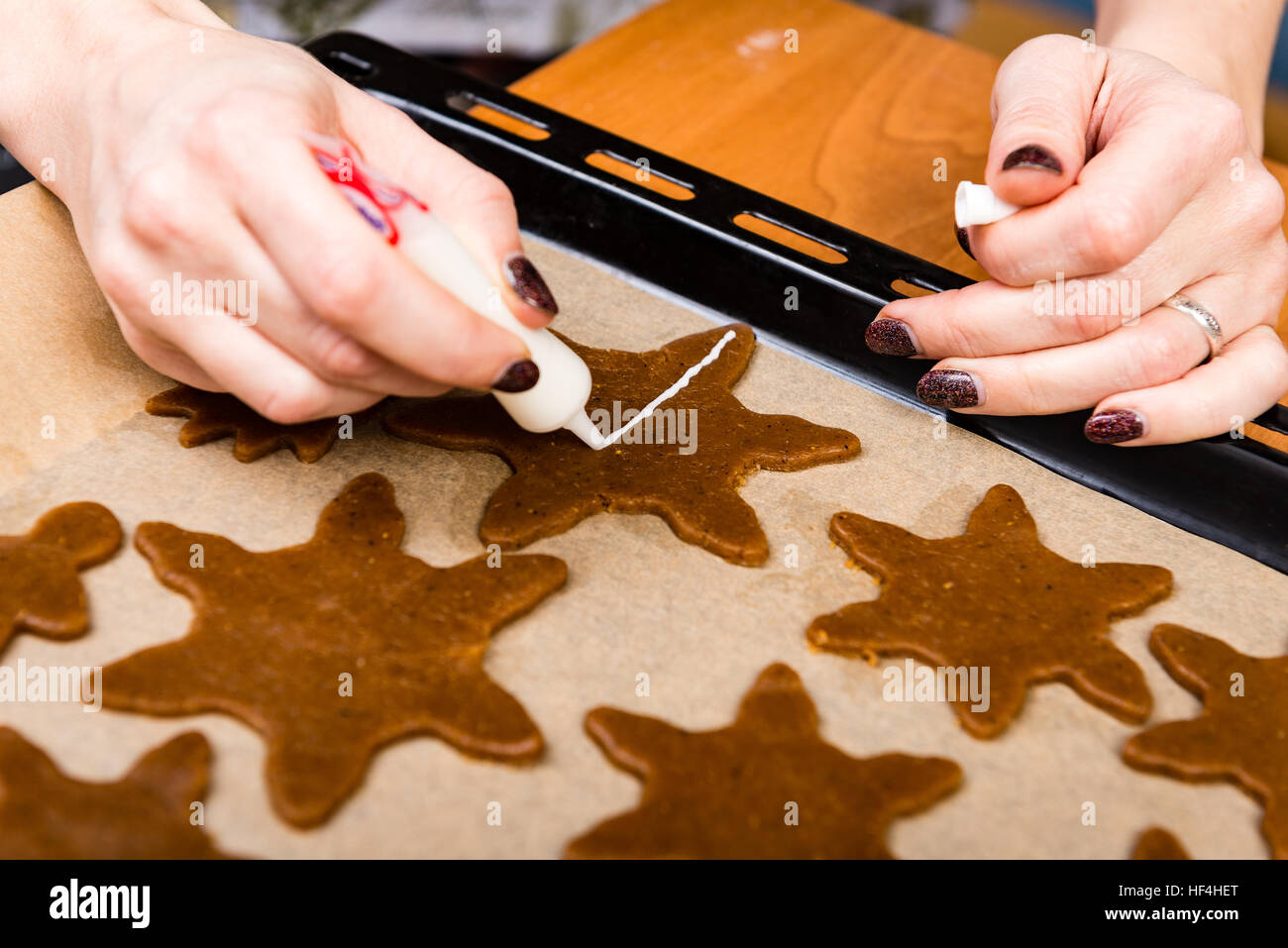 Womans hand decorating cookies with sugar. Making Gingerbread Cookies ...
