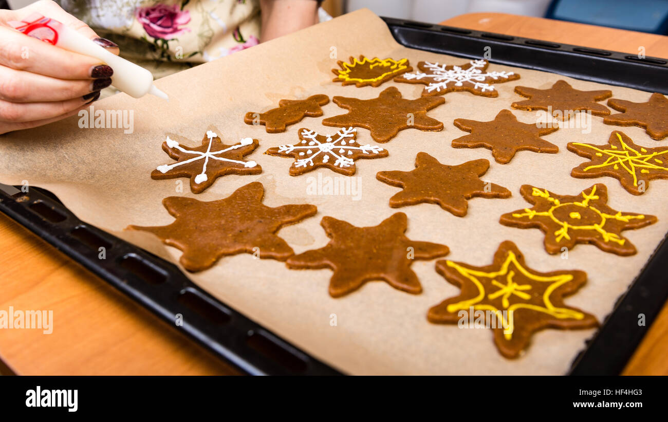 Womans hand decorating cookies with sugar. Making Gingerbread Cookies ...