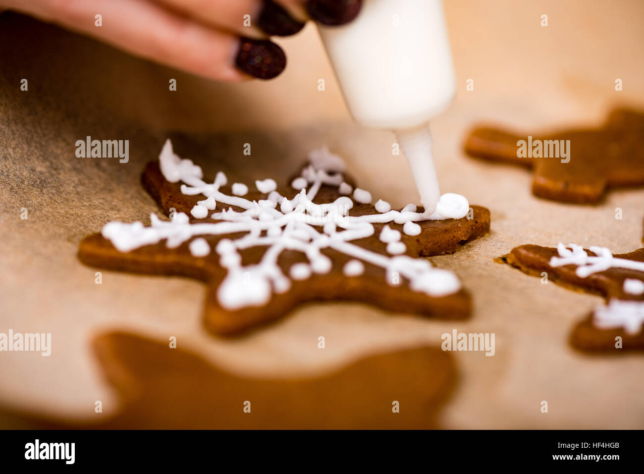 Womans hand decorating cookies with sugar. Making Gingerbread Cookies ...