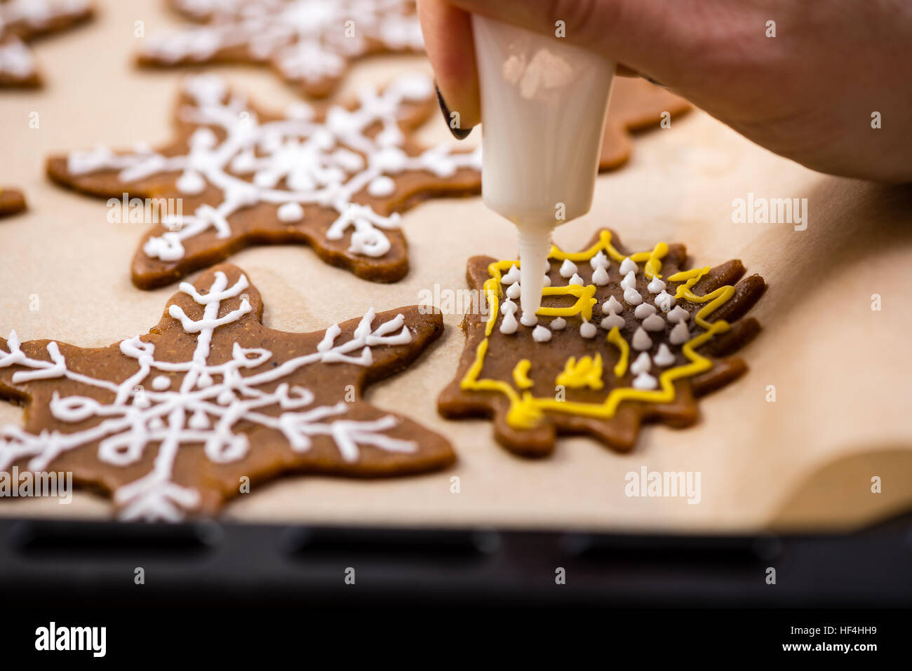 Womans hand decorating cookies with sugar. Making Gingerbread Cookies ...
