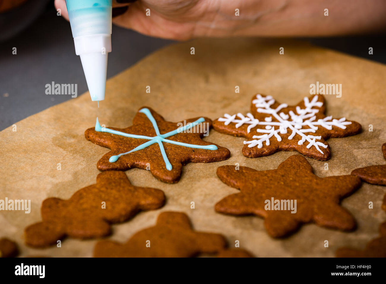 Womans hand decorating cookies with sugar. Making Gingerbread Cookies ...