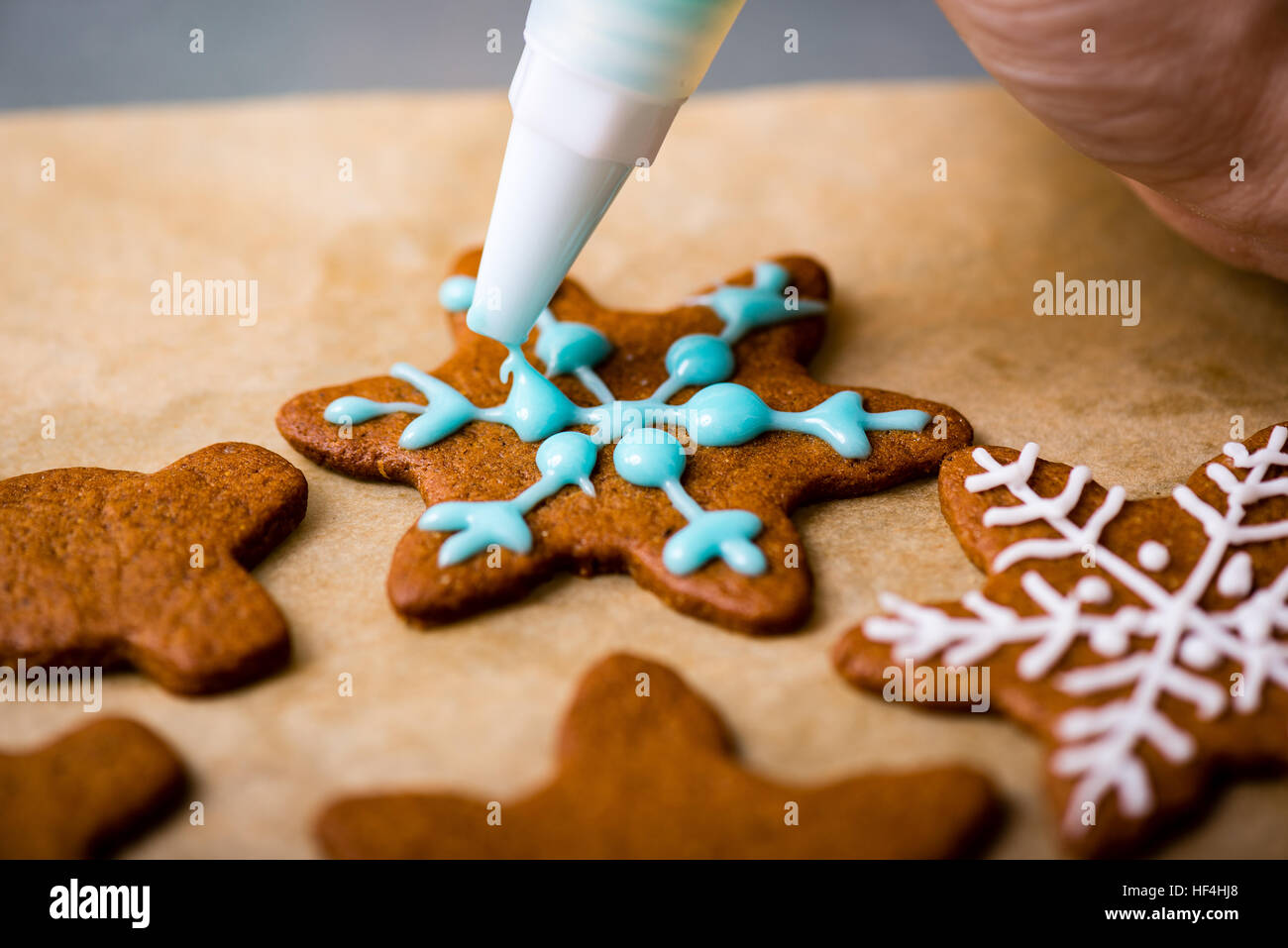 Womans hand decorating cookies with sugar. Making Gingerbread Cookies ...