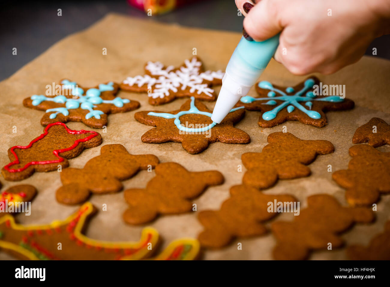 Womans hand decorating cookies with sugar. Making Gingerbread Cookies ...