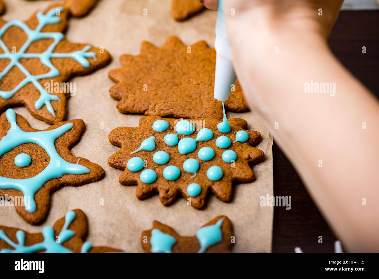 Womans hand decorating cookies with sugar. Making Gingerbread Cookies ...