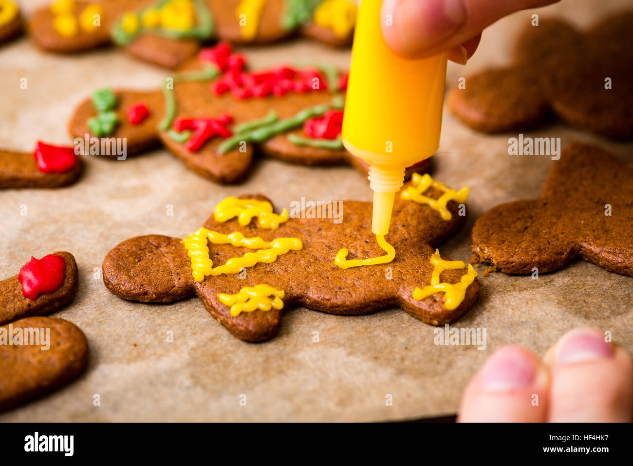 Womans hand decorating cookies with sugar. Making Gingerbread Cookies ...