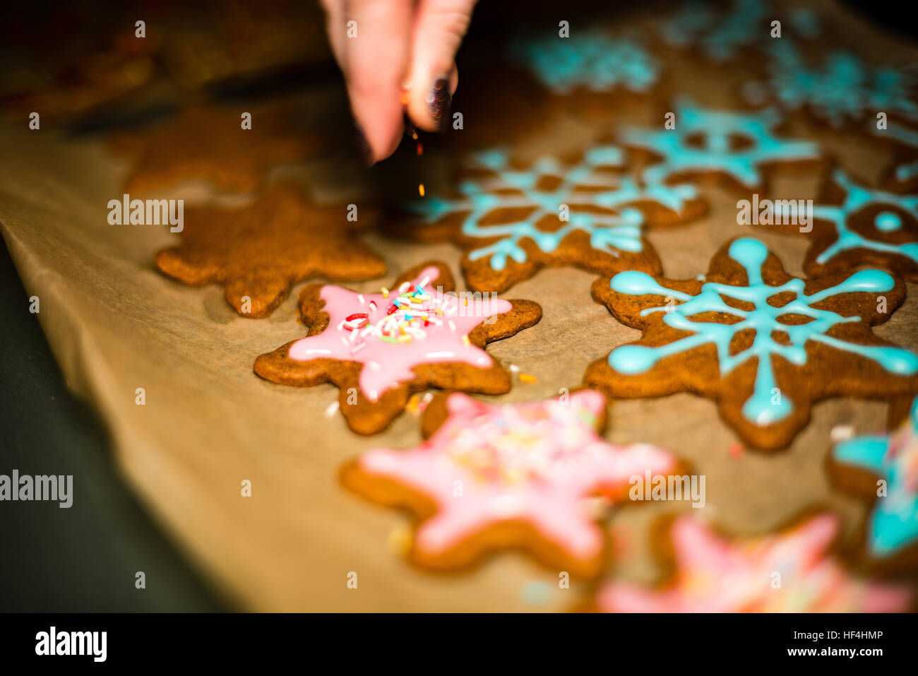 Womans hand decorating cookies with sugar. Making Gingerbread Cookies ...
