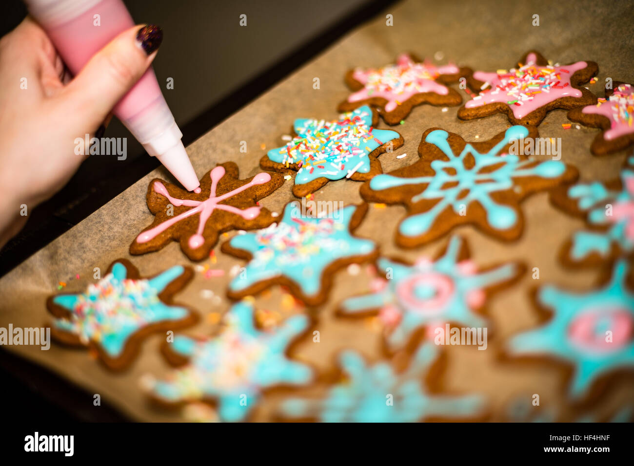 Womans hand decorating cookies with sugar. Making Gingerbread Cookies ...