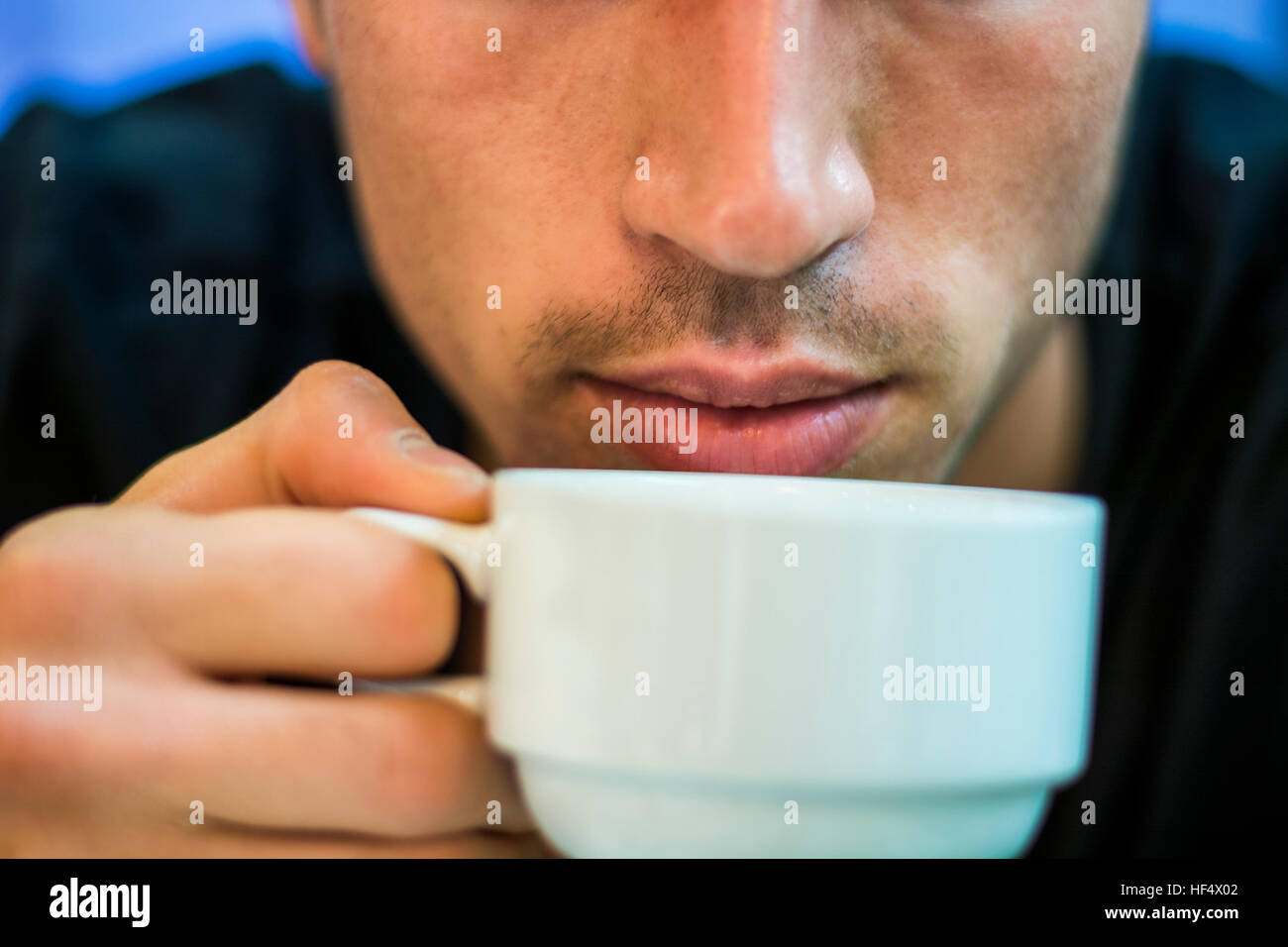 Young man drinking coffee or tea Stock Photo - Alamy