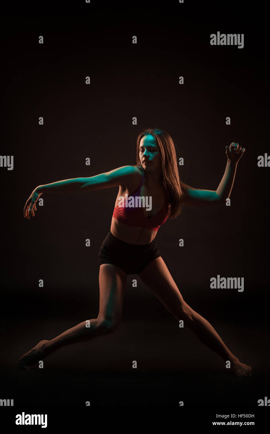 Young beautiful dancer in beige dress dancing on black studio ...