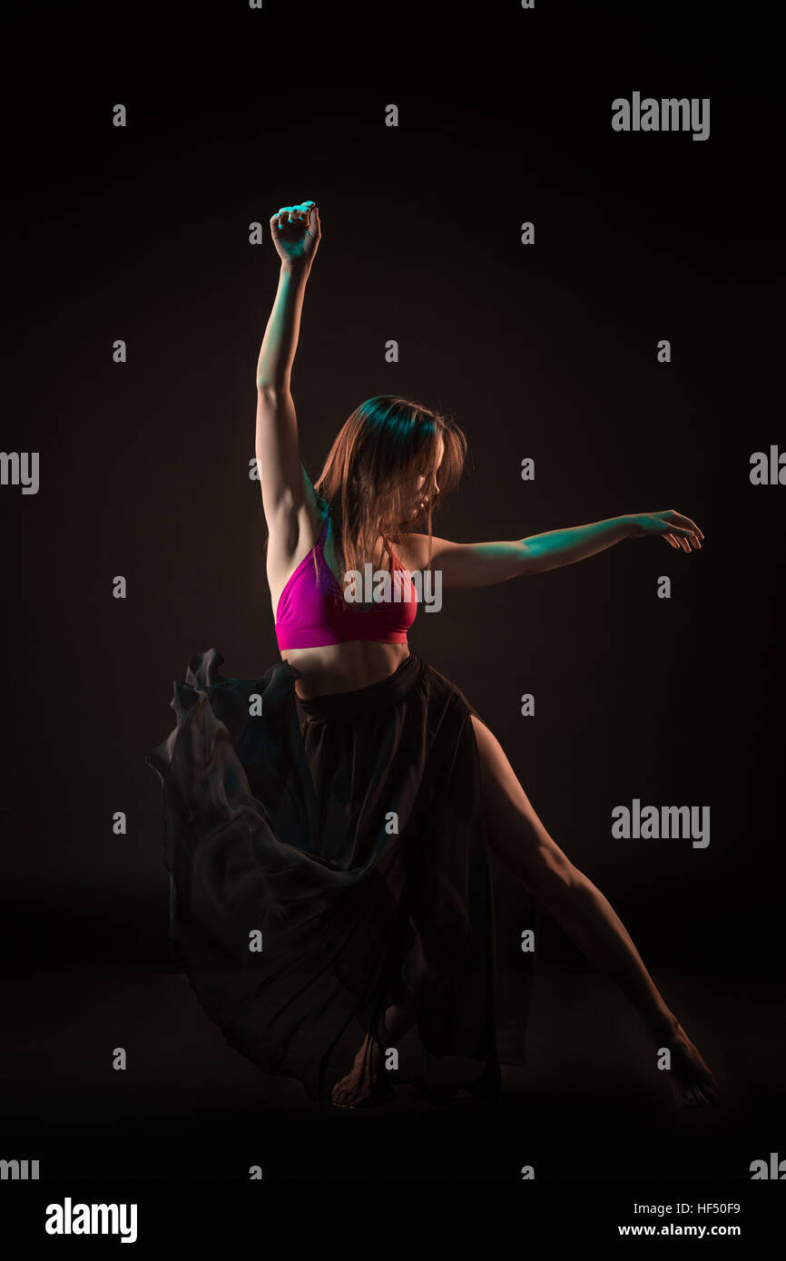 Young beautiful dancer in beige dress dancing on black studio ...