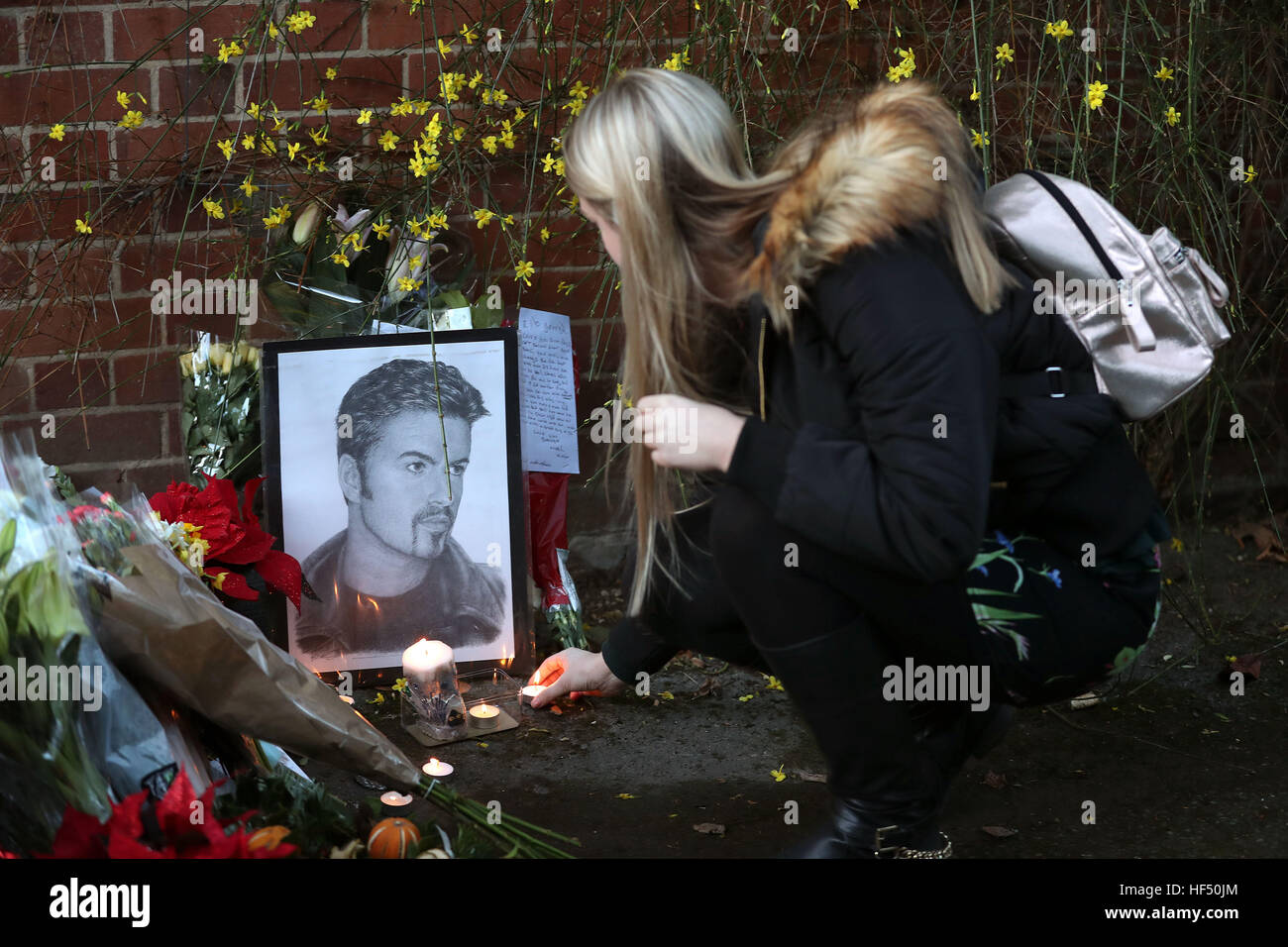 A woman lays a candle outside the Goring house of George Michael in ...
