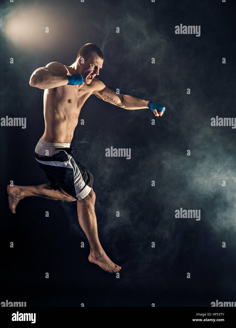 Muscular kickbox or muay thai fighter punching in jump. Smoke Stock ...