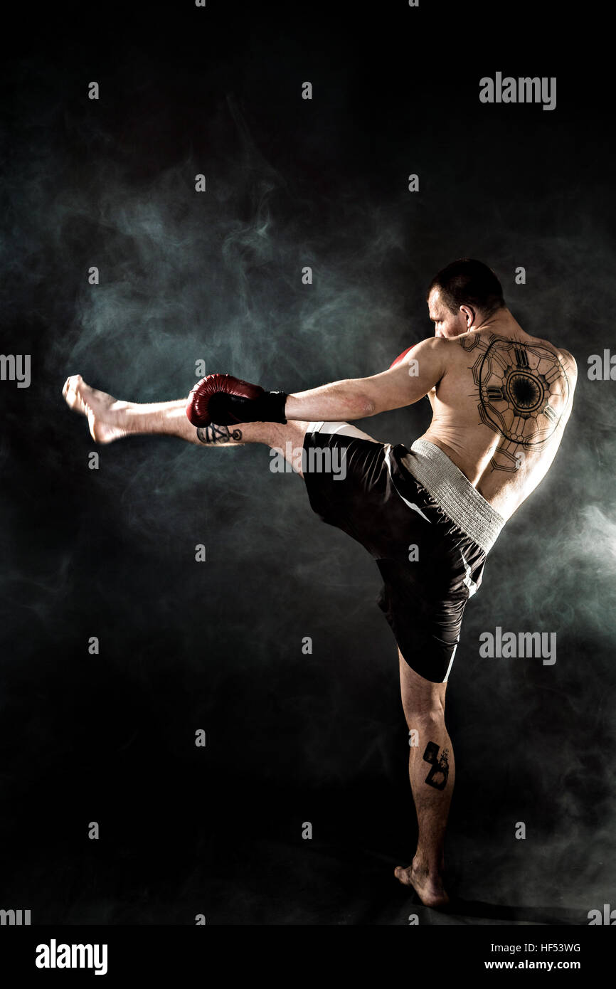 Muscular kickbox or muay thai fighter punching in smoke Stock Photo - Alamy